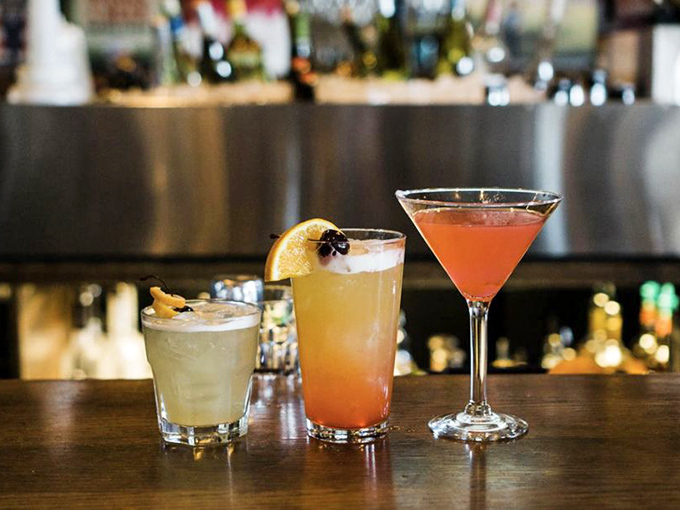 Cocktails lined up like liquid artwork. That sunset-colored concoction in the middle? It's what vacation tastes like, even on a Tuesday.