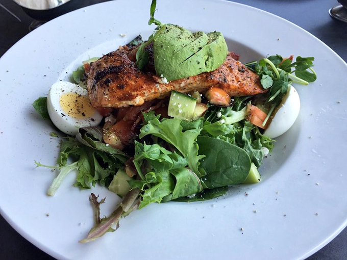 Blackened salmon atop fresh greens with avocado&mdash;proof that "healthy choice" and "absolutely delicious" aren't mutually exclusive concepts.