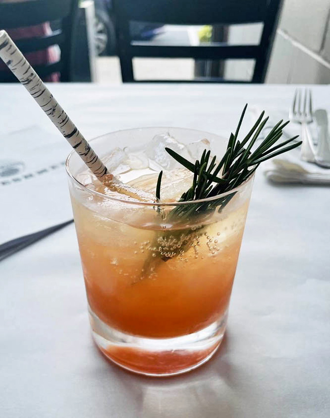 A cocktail that's dressed better than most people at the Oscars, with rosemary playing the role of sophisticated garnish against that sunset-colored backdrop.