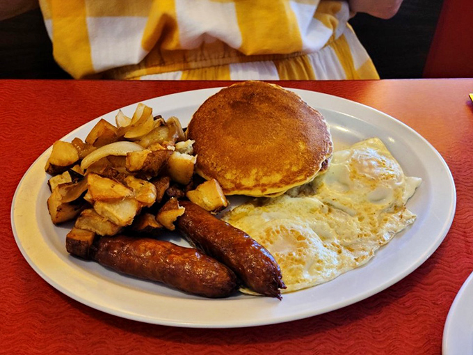 The breakfast trinity: eggs, sausage, and home fries, with a pancake standing by for sweet relief.
