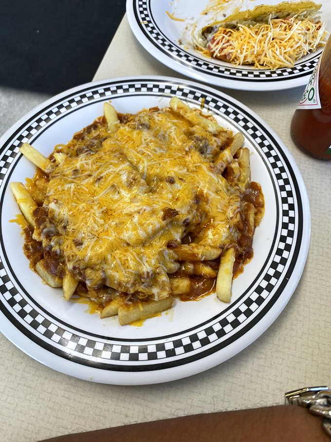 Fries achieving their highest purpose: smothered in chili and melted cheese. A fork-required masterpiece that defies dainty eating.