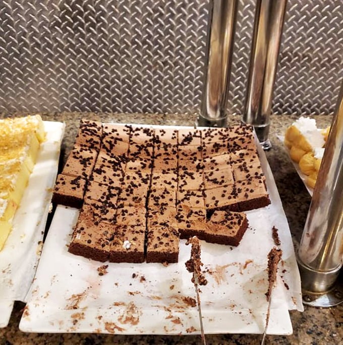 Chocolate cake squares await their destiny, each bite-sized morsel promising the perfect sweet ending to your buffet marathon. Resistance is futile.