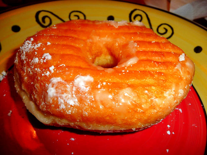 A perfect glazed donut on a colorful plate &ndash; the Beethoven's Fifth of fried dough, timeless and flawless in its simplicity.