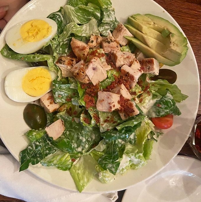 A salad that means business—crisp romaine, perfectly cooked chicken, hard-boiled eggs, and avocado arranged with the precision of a Renaissance painting.