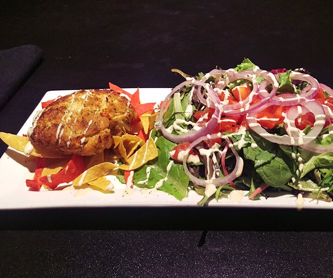 This crab cake doesn't just sit on the salad—it presides over it, with a colorful court of fresh vegetables in attendance.