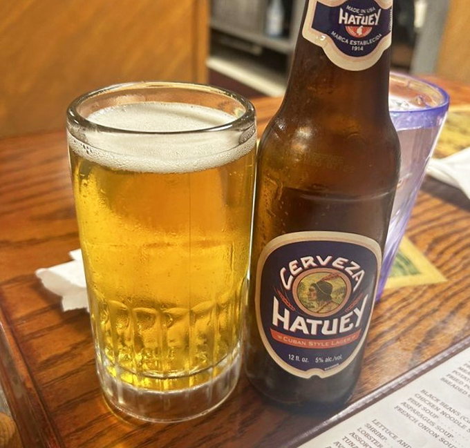 A cold Hatuey beer stands at attention, ready to cool the fire of Cuban spices and wash away the worries of whatever day you left outside.