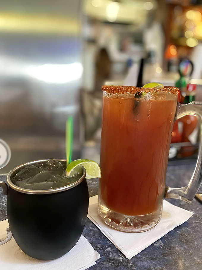 A proper Bloody Mary with a lime garnish alongside what appears to be its mysterious dark companion &ndash; because island time requires proper liquid refreshment.