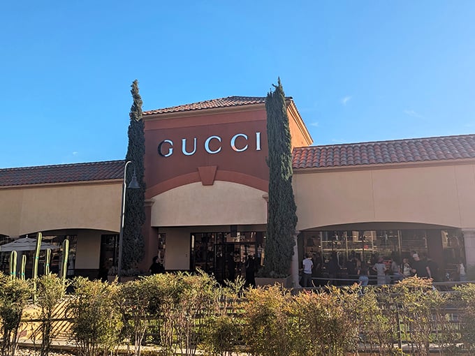 Gucci's terracotta-hued storefront stands like a temple to fashion, flanked by cypress trees. The line outside suggests worship is in progress.