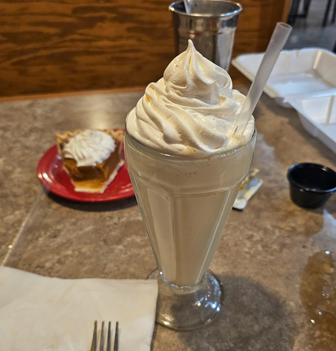 This isn't just a milkshake; it's a tower of creamy nostalgia topped with a cloud of whipped cream that defies both gravity and restraint.