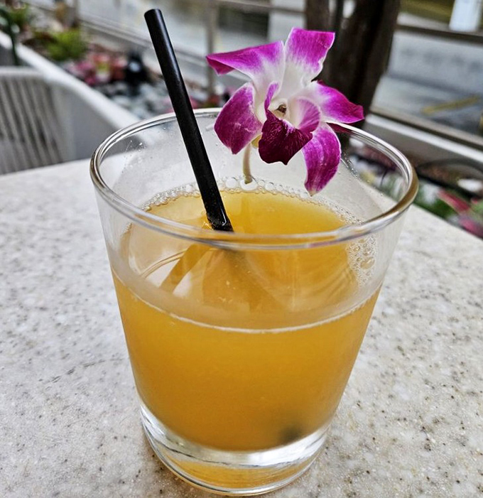 A glass of liquid sunshine garnished with an orchid&mdash;because in Hawaii, even your juice deserves to dress up for breakfast.