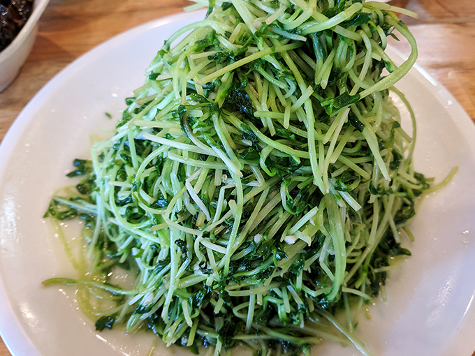 A mountain of pea shoots arrives looking impossibly green and fresh, glistening with just enough garlic.