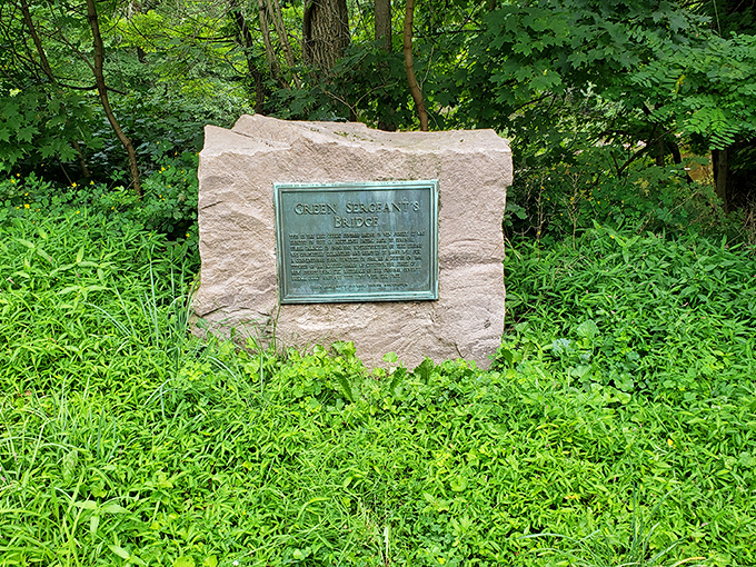 The historical plaque tells tales of bygone eras, nestled among spring greenery like a hidden storybook.