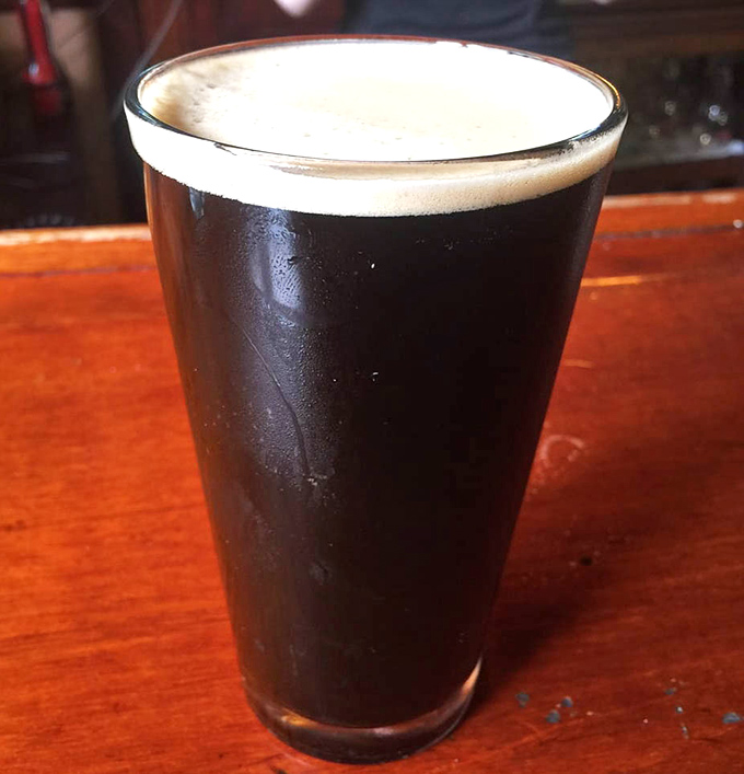 A properly poured pint of dark beer sitting on a well-loved bar top&mdash;sometimes the simplest pleasures are the ones we travel farthest to find.