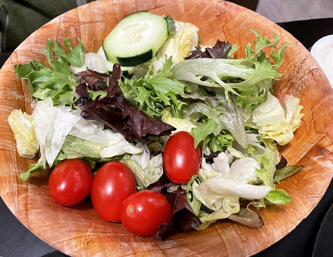 A fresh garden salad that serves as either virtuous counterpoint or strategic palate cleanser between wing assaults. Choose your adventure.