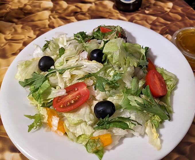 A house salad that actually looks like someone cared. Crisp greens, ripe tomatoes, and olives providing that perfect pre-pizza palate cleanser.