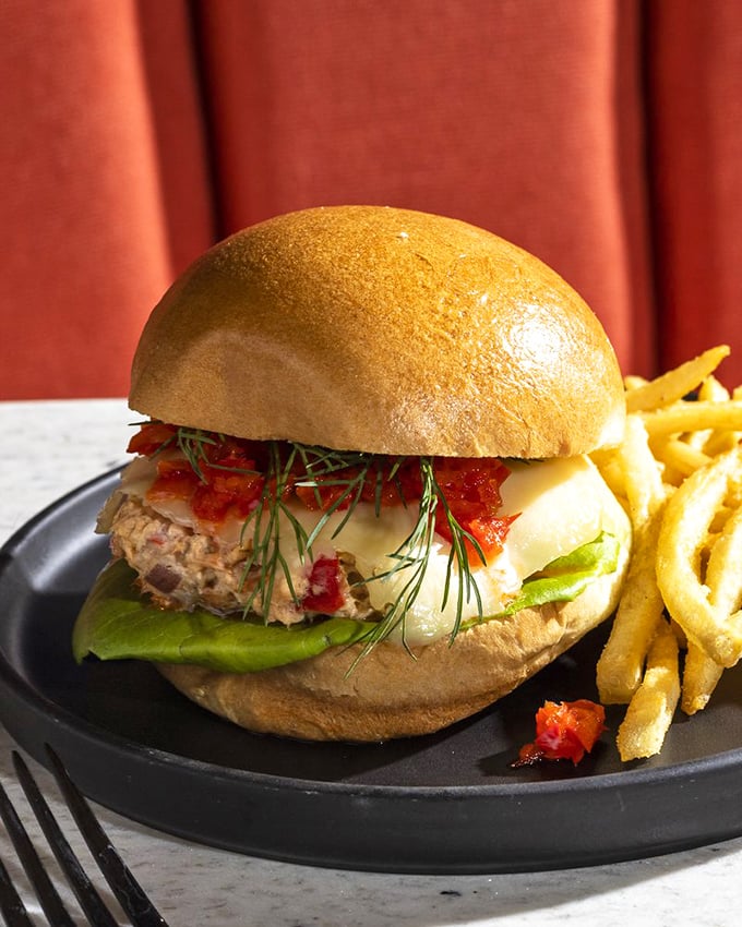 A sandwich that bridges the health-indulgence divide: flaky salmon, melty cheese, and fresh herbs on a pillowy bun that would make Neptune proud.