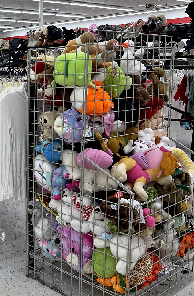 A wire cage overflowing with stuffed animals, like a zoo where every creature costs less than a fancy coffee and needs a forever home.