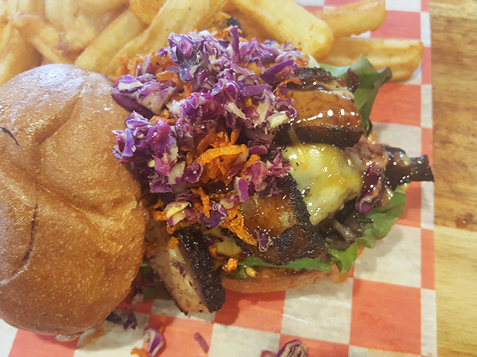 A burger that requires both hands and a strategy. Topped with purple slaw and melty cheese, it's architecture and art on a brioche bun.