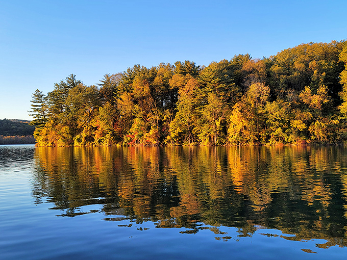 Fall's fiery palette reflected in still waters creates nature's perfect mirror image. Autumn doesn't just arrive here&mdash;it performs.