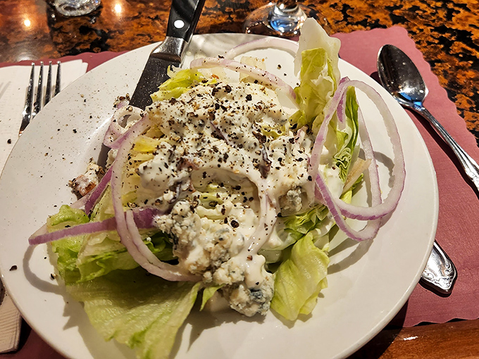 The wedge salad – where iceberg lettuce finally gets the respect it deserves under a blanket of blue cheese and red onions.