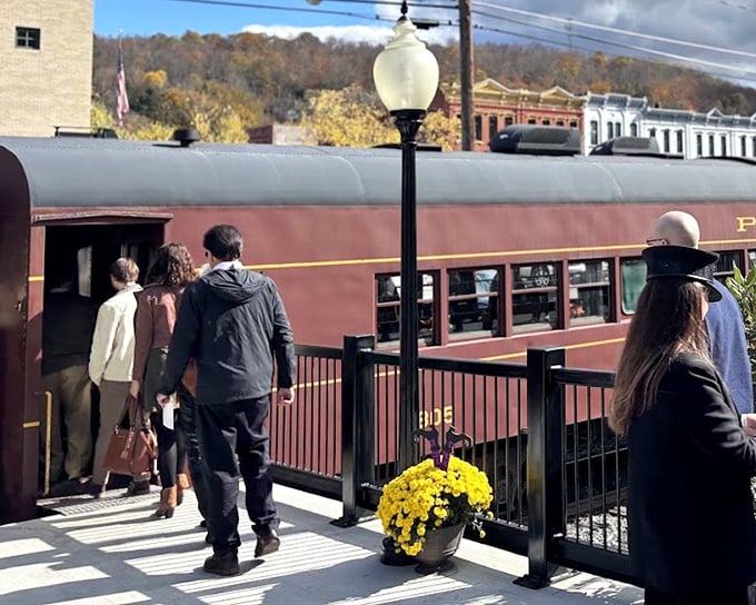 All aboard! Passengers step into history at the boarding platform, where fall foliage provides a golden-red carpet worthy of this railway journey.