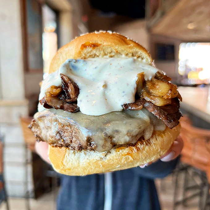 Melted cheese cascades over caramelized mushrooms on this burger beauty &ndash; proof that sometimes the best relationships are the messiest ones.