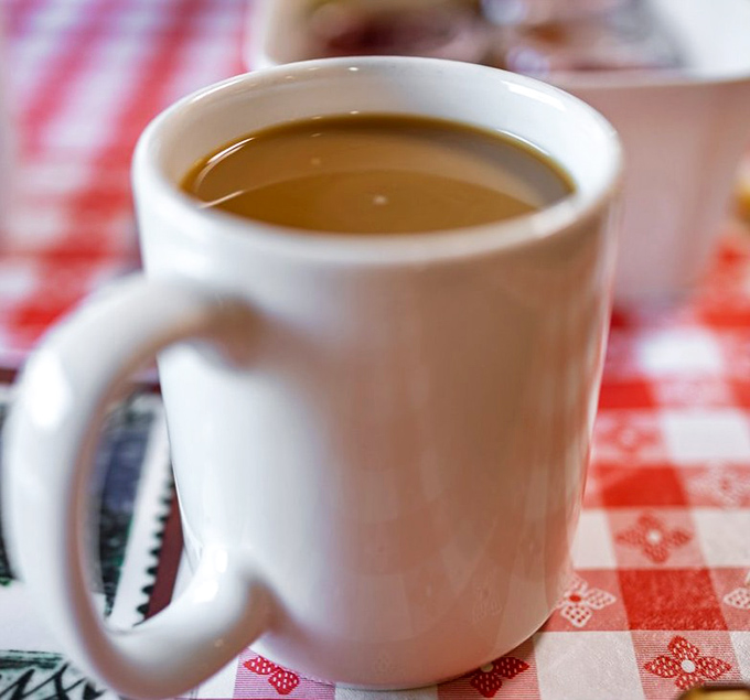 Hot coffee in a classic white mug on a checkered tablecloth&mdash;sometimes simple perfection needs no explanation.