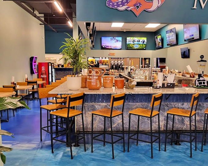 The bar area combines modern design with coastal charm. Those blue floors make you feel like you're walking on water&mdash;before the margaritas even arrive!