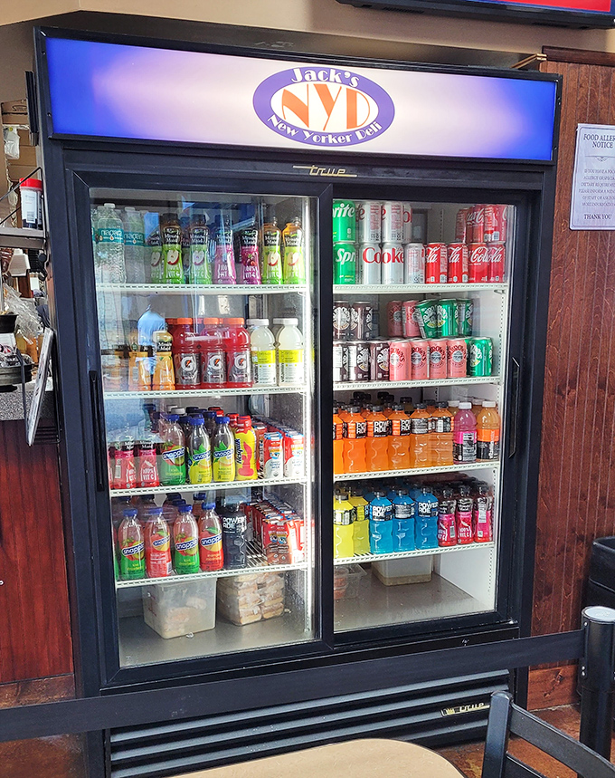 The drink cooler stands like a colorful oasis of possibility, offering everything from classic Coke to those fancy waters people pretend to enjoy.