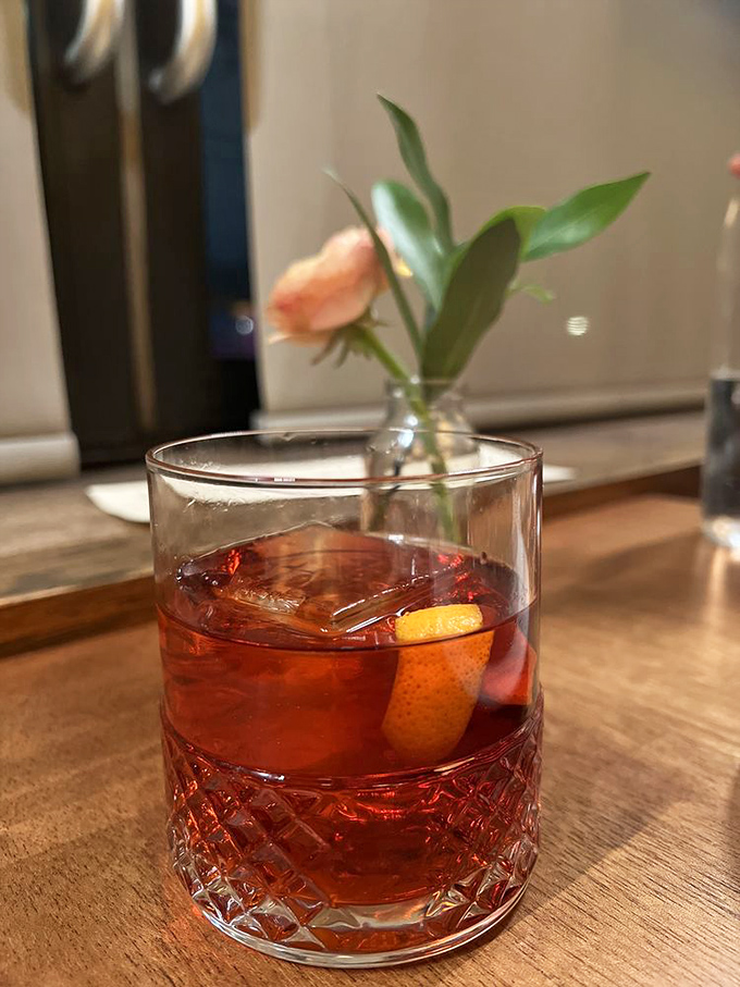 A classic Negroni garnished with orange and a delicate flower&mdash;the kind of cocktail that makes you want to linger until closing time.