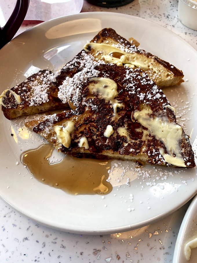 French toast that's dressed for success, dusted with powdered sugar and drizzled with maple syrup like it's ready for its close-up.