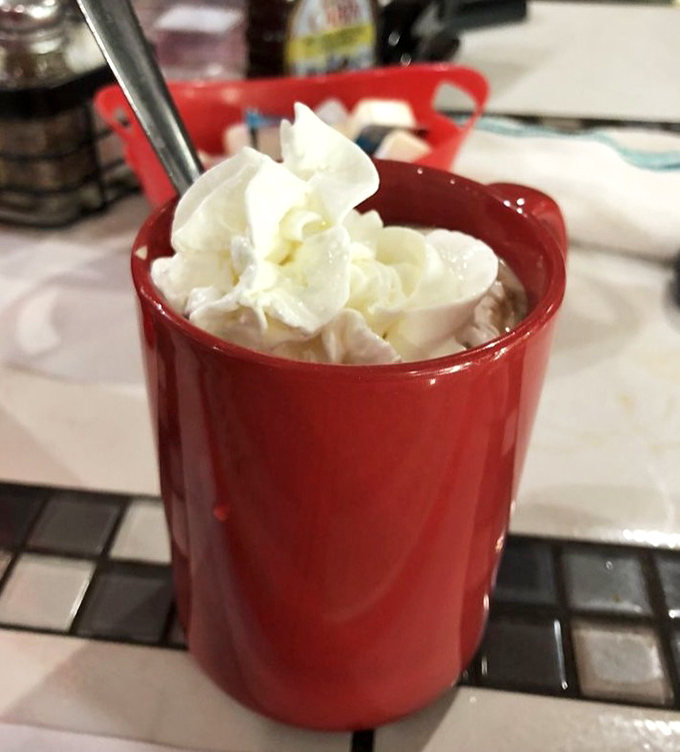 Hot chocolate topped with a cloud of whipped cream in a cheerful red mug. Some mornings call for liquid dessert disguised as a beverage.