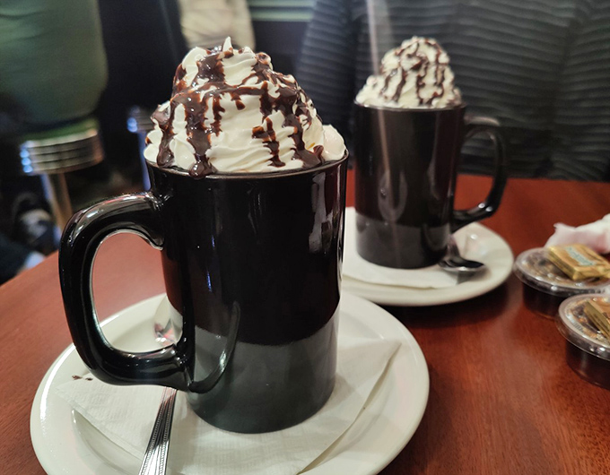 Hot chocolate that doesn't know the meaning of restraint. That whipped cream mountain with chocolate drizzle is what childhood dreams are made of.