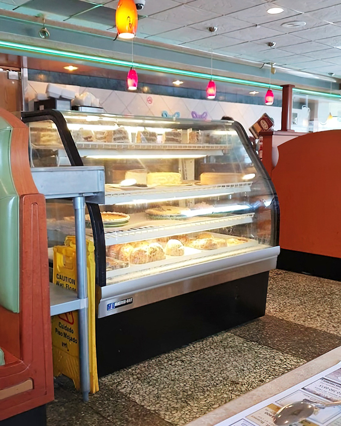 The dessert case—where willpower goes to die. Those colorful pendant lights are just spotlights for the real stars behind the glass.