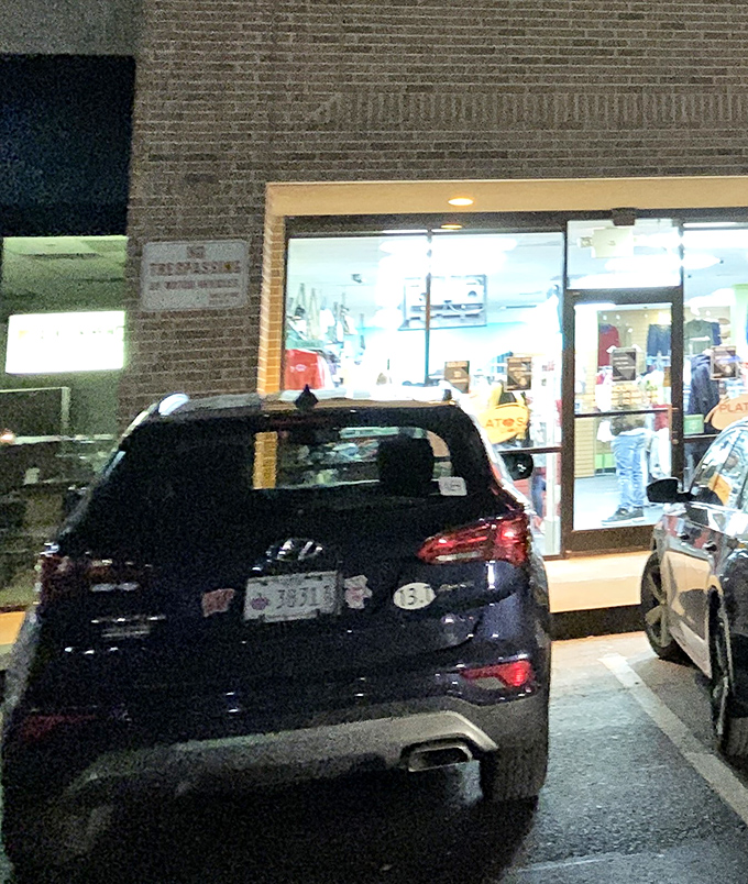 Even at night, fashion seekers find their way to these doors. The parking lot fills with cars carrying empty trunks soon to be filled.