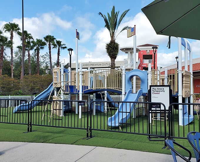 The playground oasis where children burn energy while parents contemplate burning credit cards. A tactical shopping break disguised as family-friendly amenity.
