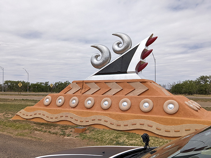 Even against cloudy skies, the monument's silver swooshes shine like the chrome dreams that once cruised this legendary highway.