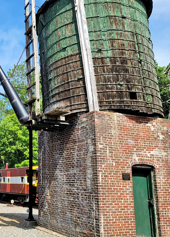 The weathered wooden water tower, essential for steam locomotives, stands like a sentinel of the past. Its patina tells stories of countless trains refreshed beneath it.