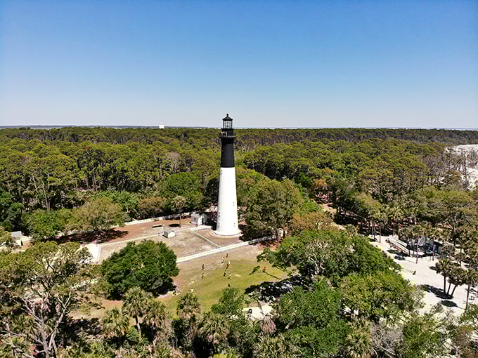 Hunting Island's lighthouse stands tall against a backdrop of lush greenery, a black-and-white sentinel guarding the coast.