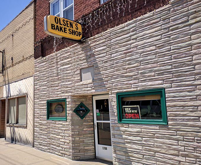 That weathered stone facade has witnessed decades of early morning donut runs and satisfied customers.