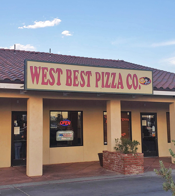 West Best Pizza Company's simple storefront proudly flies American flags, a patriotic pizza oasis in the California desert.