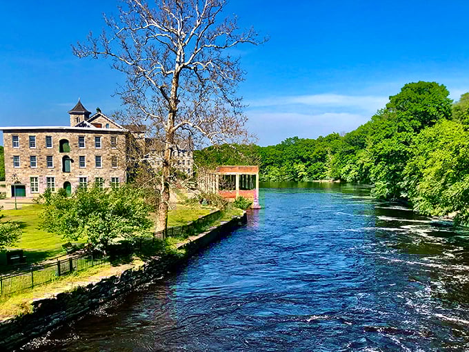 That old stone mill building beside the rushing water holds stories of industry when water power meant actual water, not utilities.