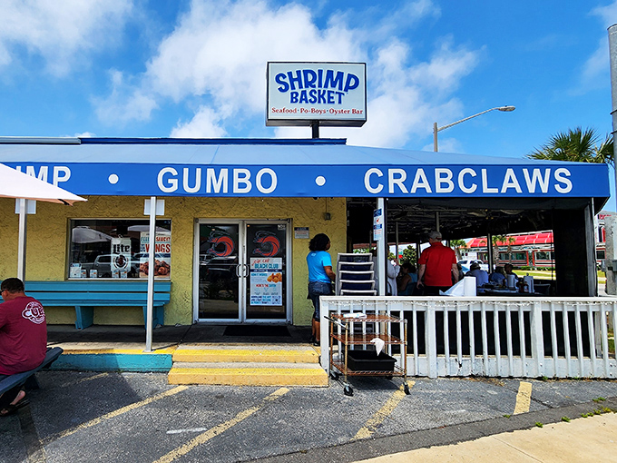 Bright blue skies match The Shrimp Basket cheerful awning, where "GUMBO &bull; CRABCLAWS" isn't just signage&mdash;it's a promise of Gulf Shores greatness.