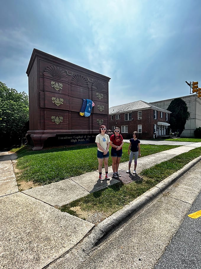 Three visitors capture the perfect scale shot. Nothing says "I was here" like being dwarfed by an enormous piece of household furniture.