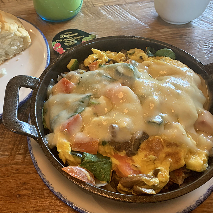 The breakfast skillet arrives sizzling with eggs, vegetables, and cheese&mdash;a cast iron symphony of morning perfection.