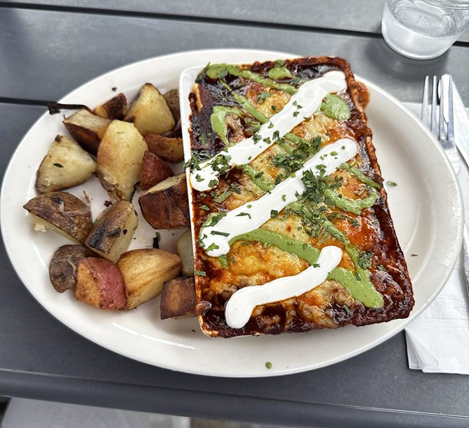 A breakfast burrito that demands to be photographed before eaten - layers of egg, cheese, and vegetables under a zigzag of creamy sauce.