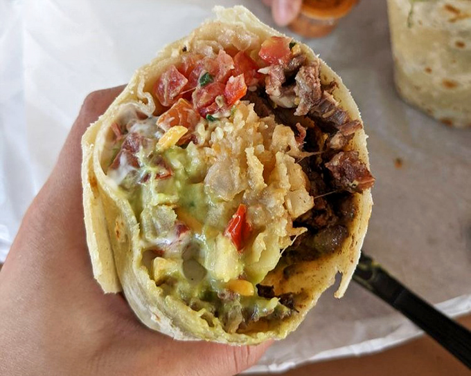The California burrito reveals its secrets: French fries nestled among carne asada like potato treasures in a tortilla treasure chest.