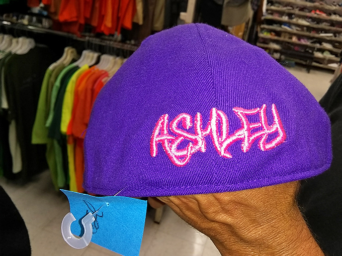 This purple "ASHLEY" cap isn't just headwear &ndash; it's either someone's discarded identity or your next ironic fashion statement.