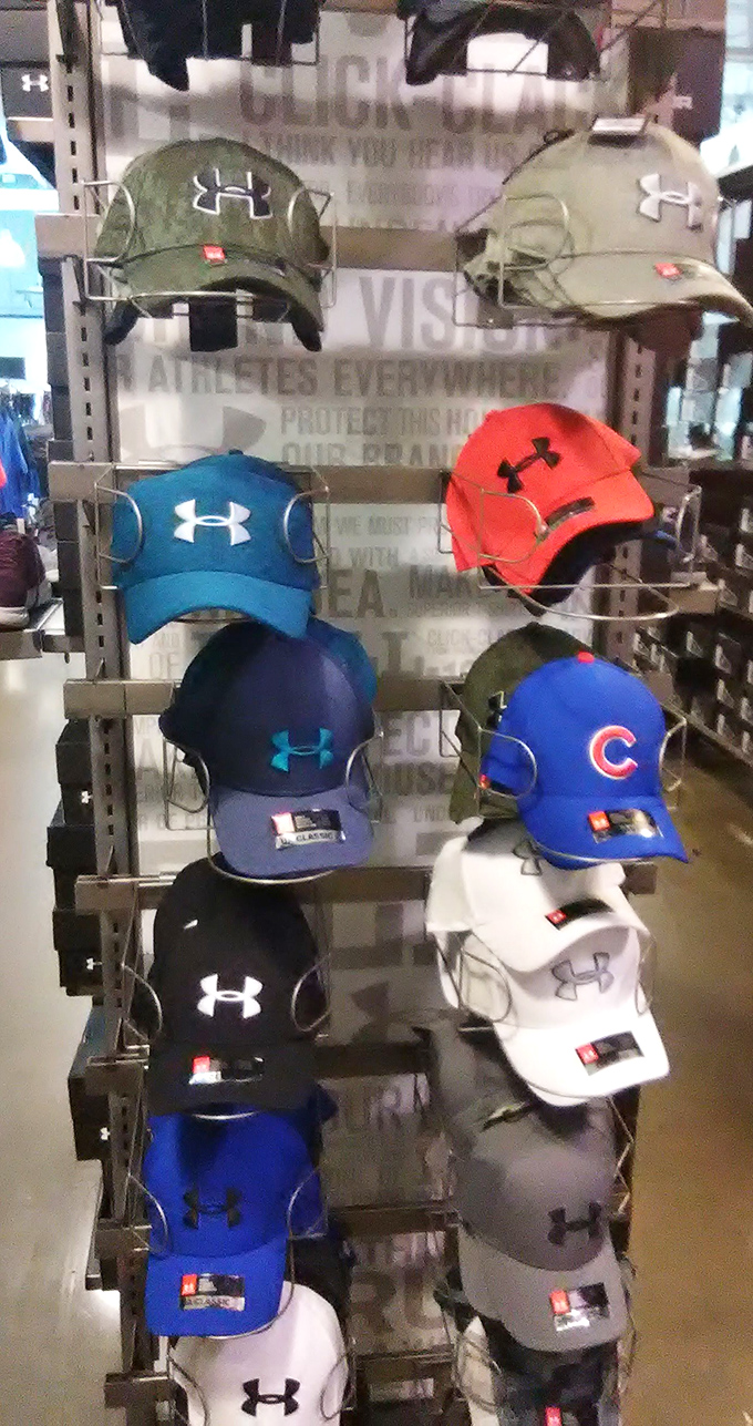 Under Armour caps lined up like colorful soldiers, ready to protect you from both sun and the shame of paying full retail price.