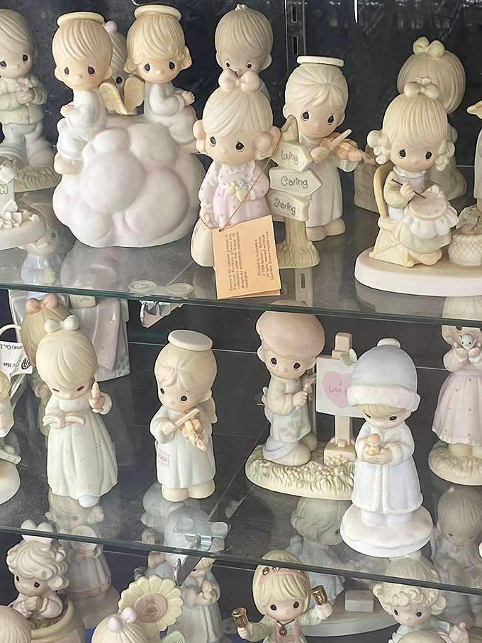 Precious Moments figurines stand in silent formation, their teardrop eyes watching generations of collectors debate which one completes their set. 
